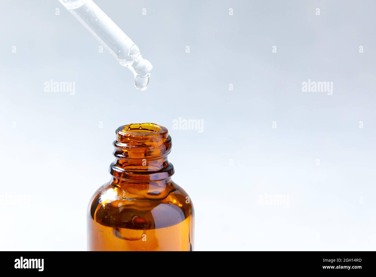 Essential oil dropping from pipette to bottle. Essence liquid cosmetic ...