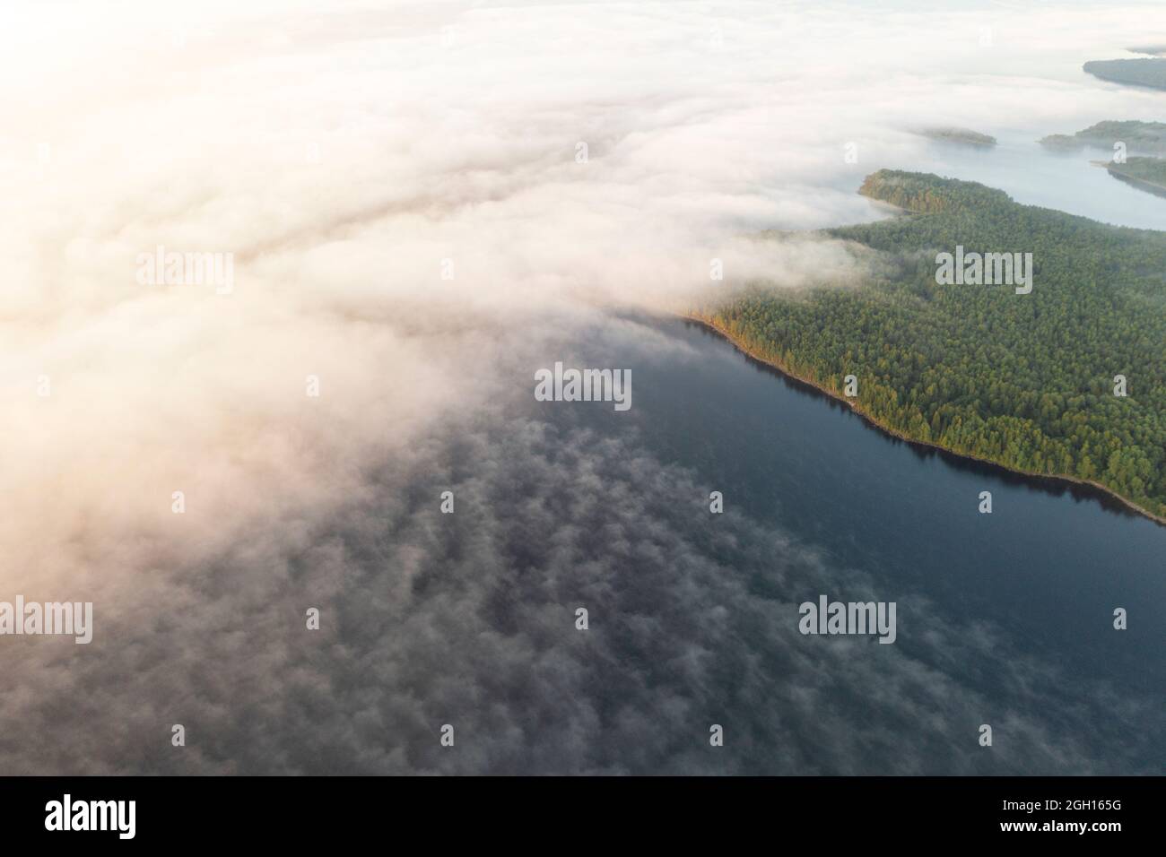 Aerial view lake with fog above water surface and sunrise over forest ...