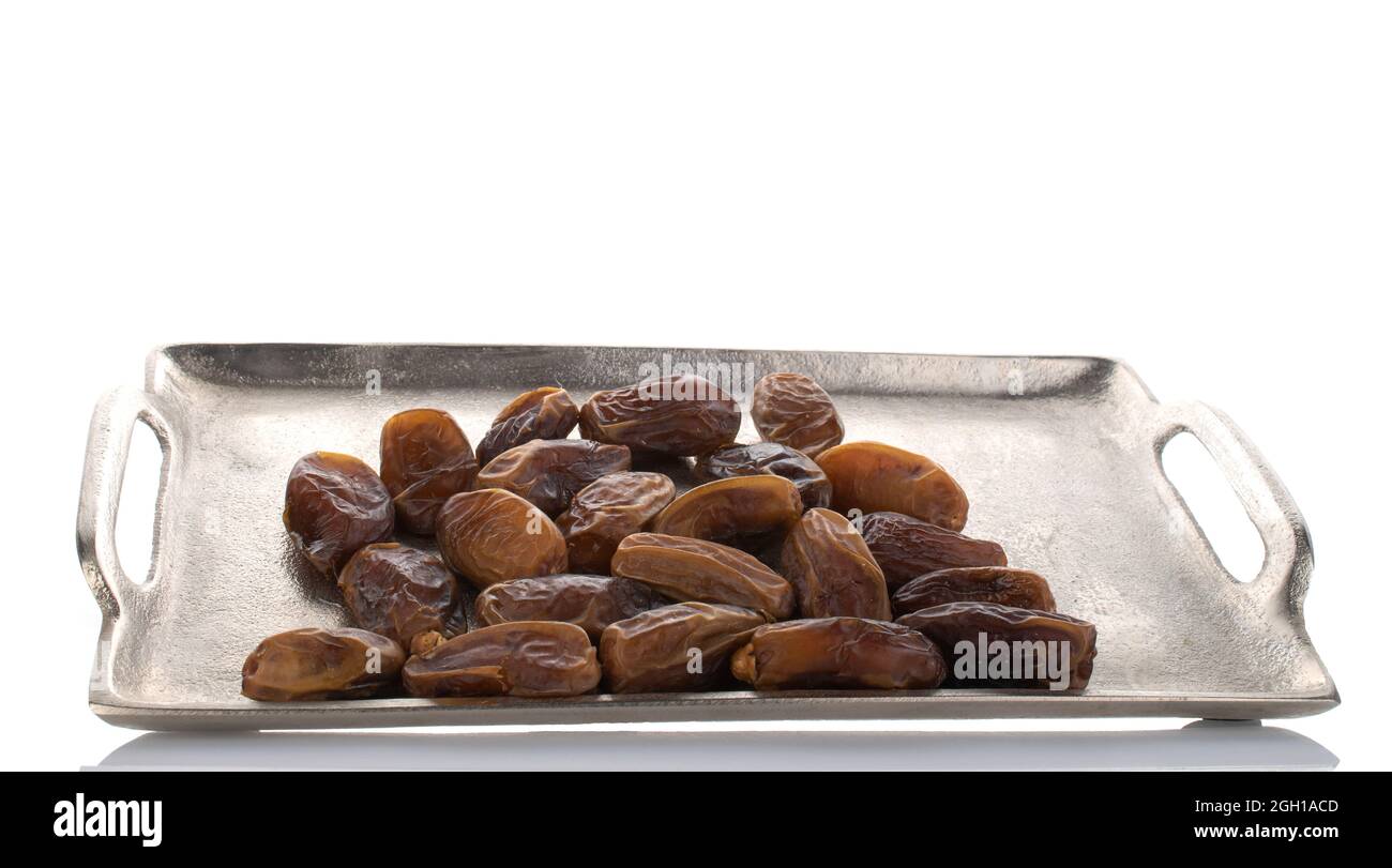 Several dried organic light brown dates on a metal tray, close-up ...