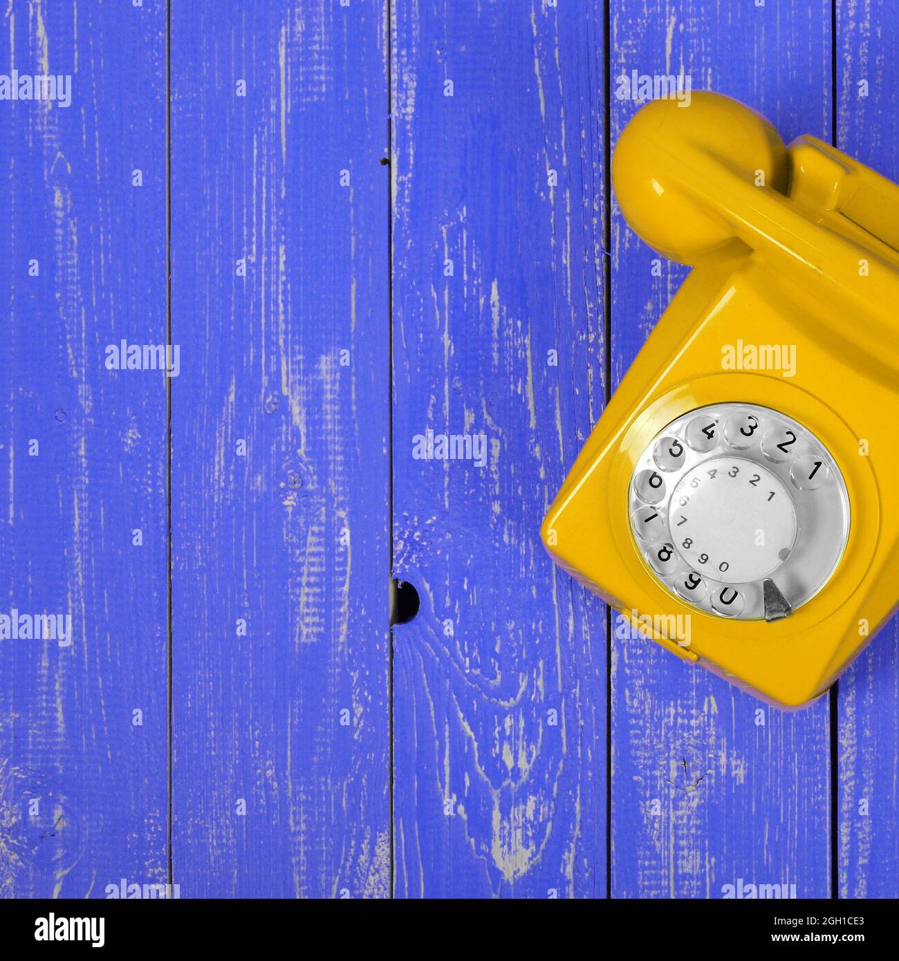 Vintage Phones - Top view Yellow retro telephone on a blue wooden ...