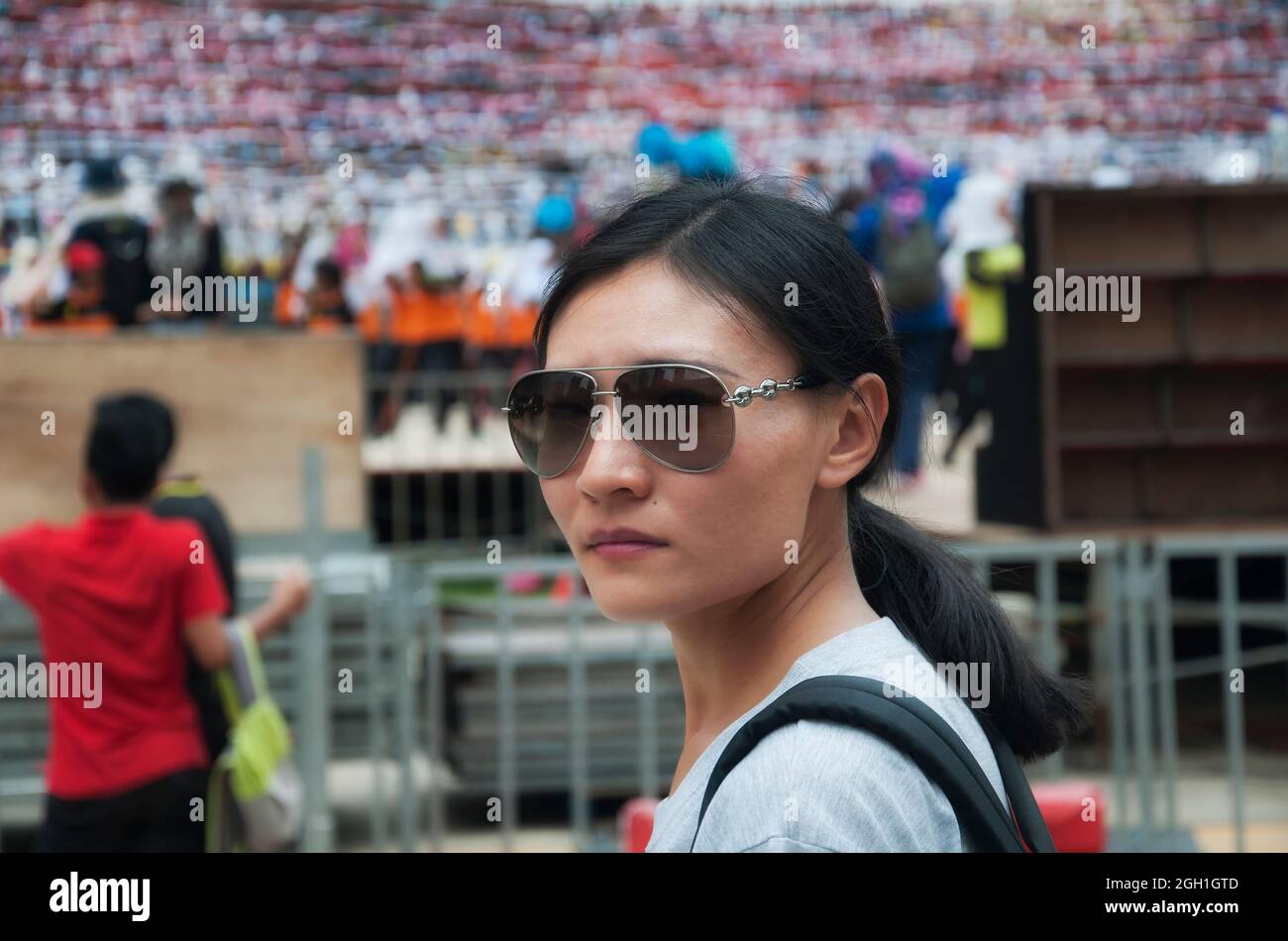a chinese woman looking at the camera with a blurred crowd picture in ...