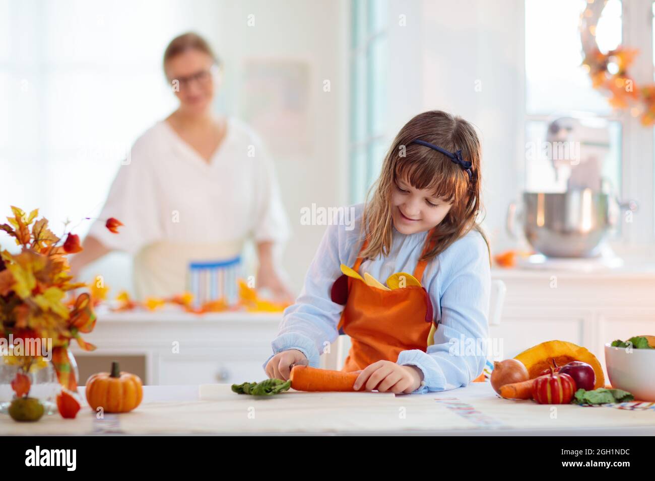 Family cooking Thanksgiving dinner. Grandmother and child cut pumpkin ...