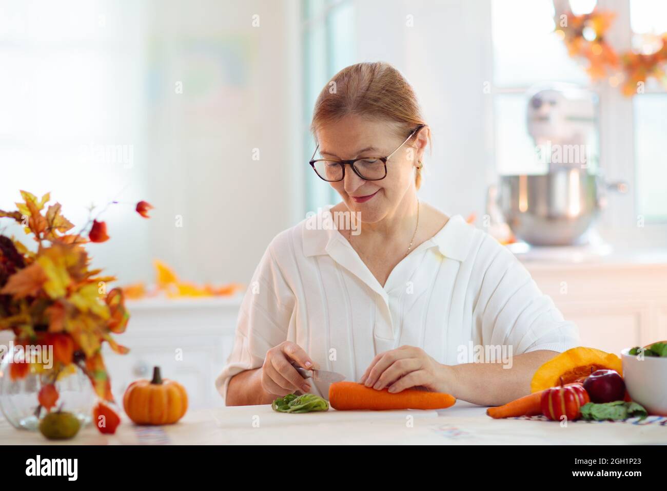 Thanksgiving dinner preparation. Woman cutting pumpkin, carrot and ...