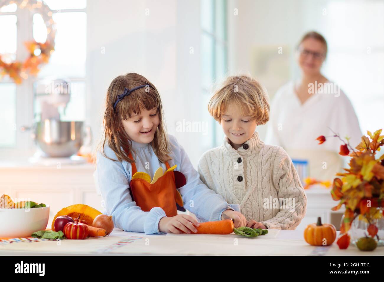 Family cooking Thanksgiving dinner. Grandmother and child cut pumpkin ...