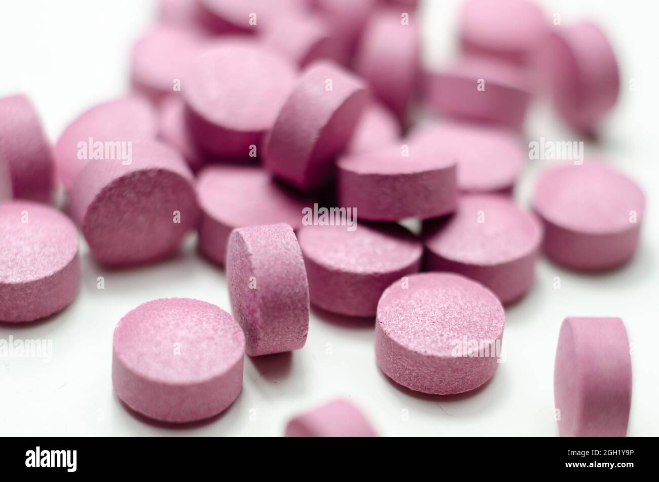 Purple pills scattered on a white background, food supplements which ...