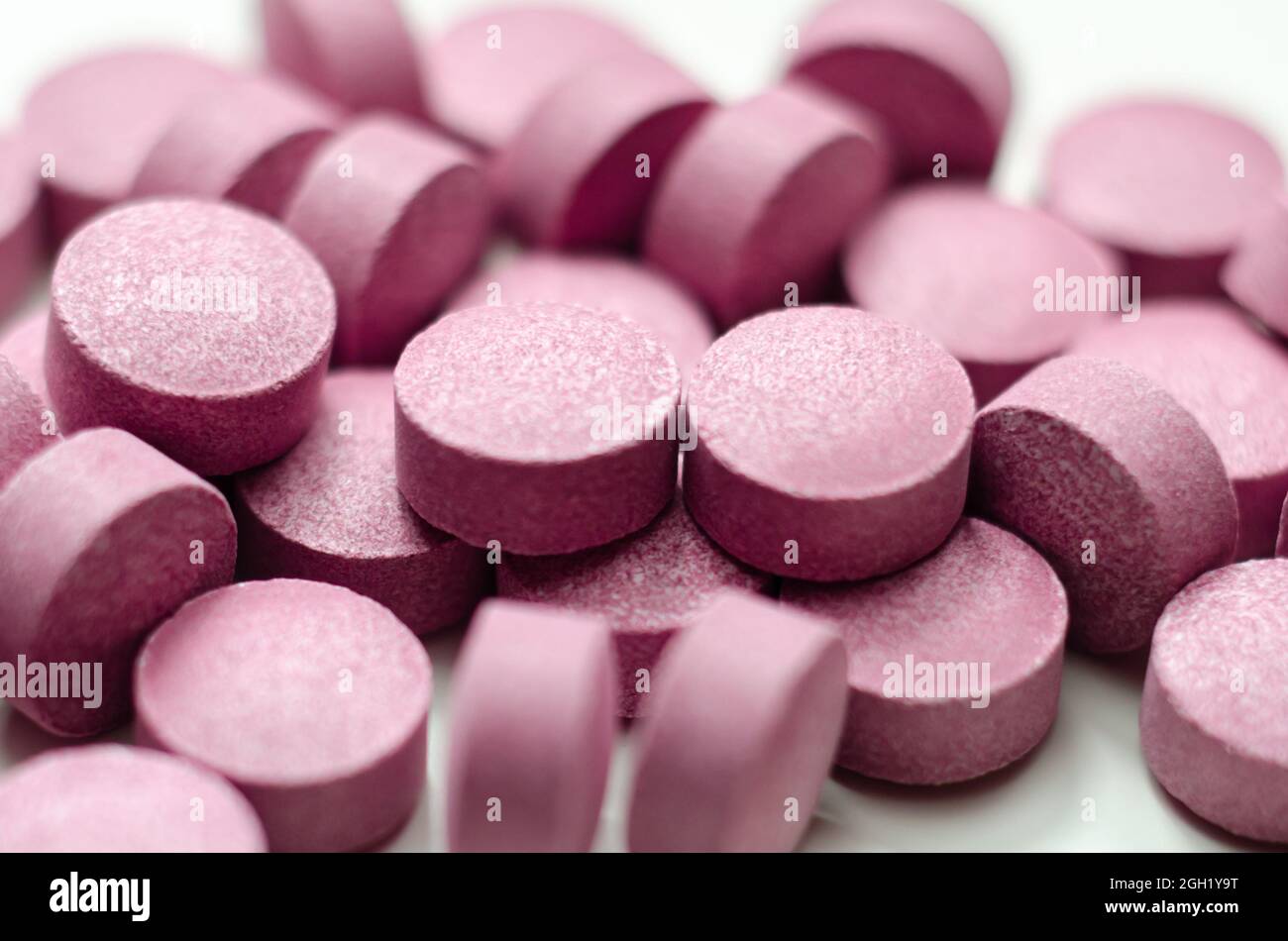 Purple pills scattered on a white background, food supplements which ...