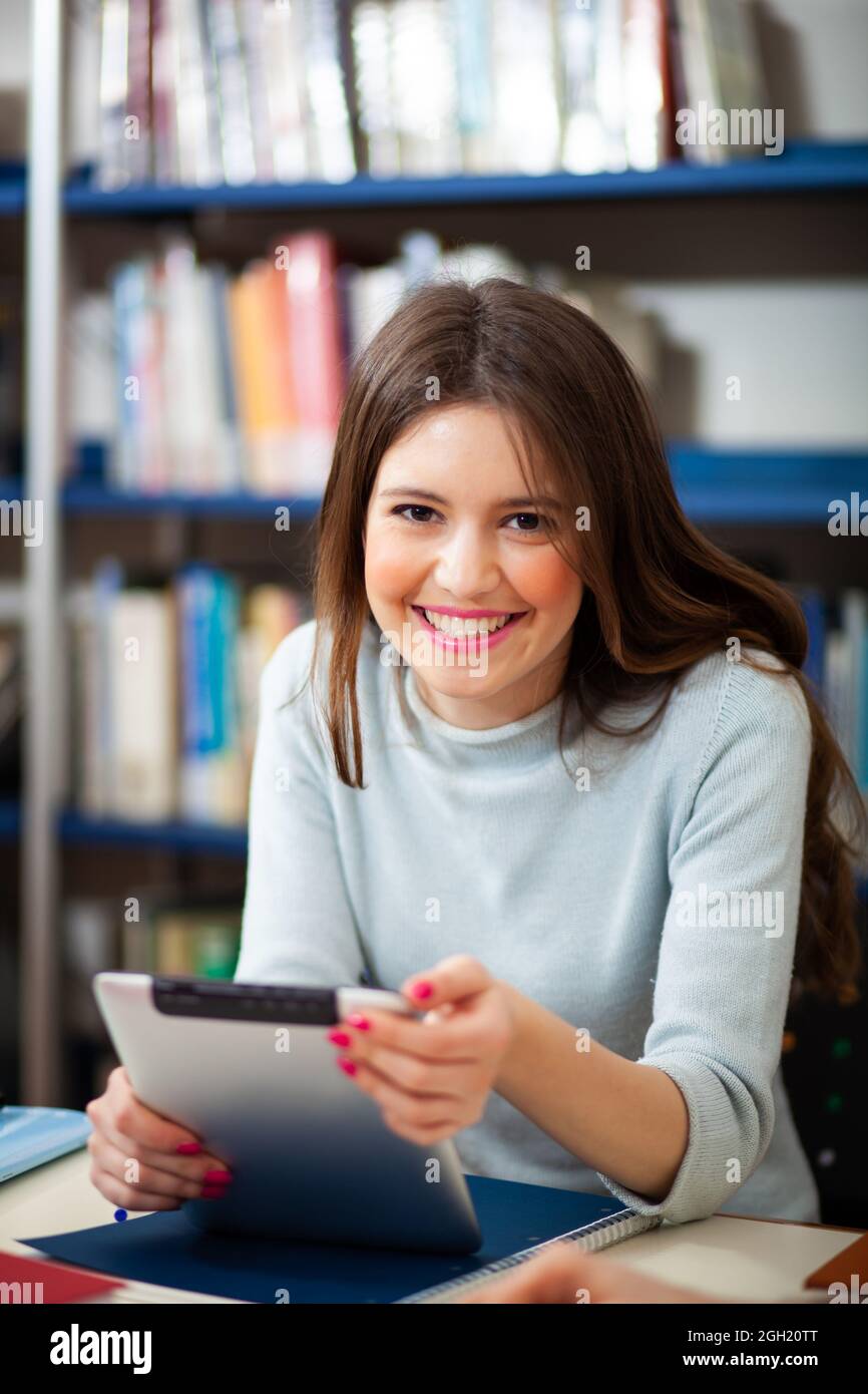 Female student using a tablet in a library Stock Photo - Alamy