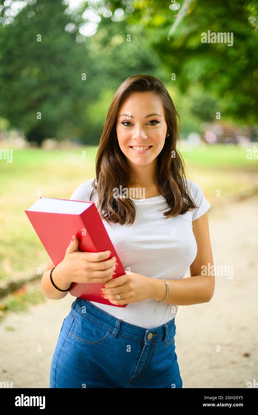 Beautiful female student holding a book outdoor Stock Photo - Alamy