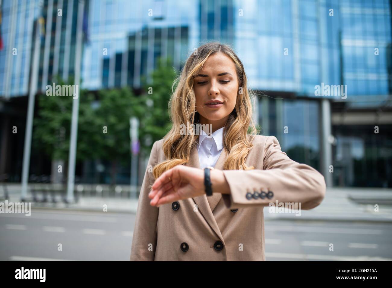 Confident young female manager checking the time on her watch outdoor ...