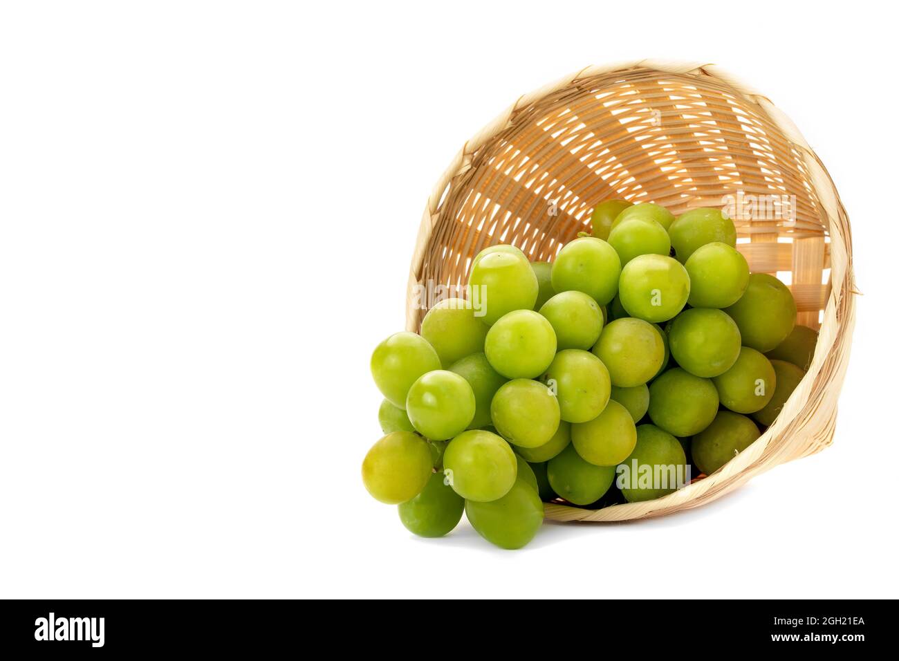 A bunch of green grapes in a weave bamboo basket. Isolated on white ...