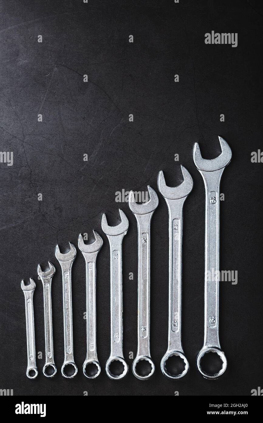 A set of wrenches on a textured black background in a row. Top view ...