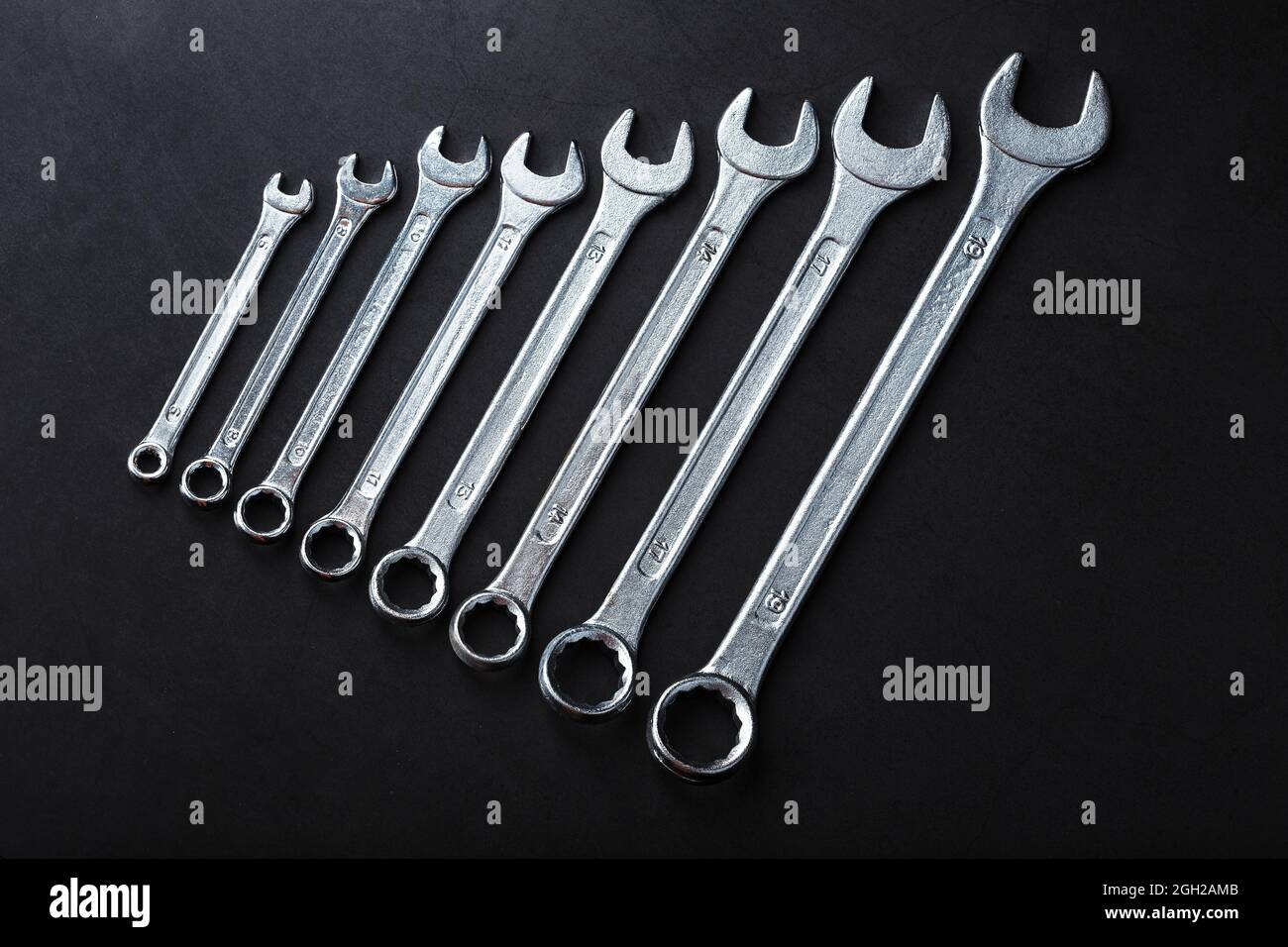 A set of wrenches on a textured black background in a row. Top view ...