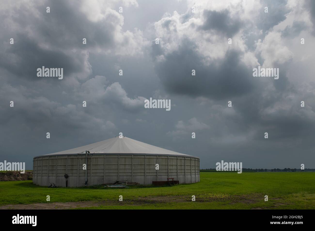 Round concrete manure silo on a meadow in the summer with threatening ...