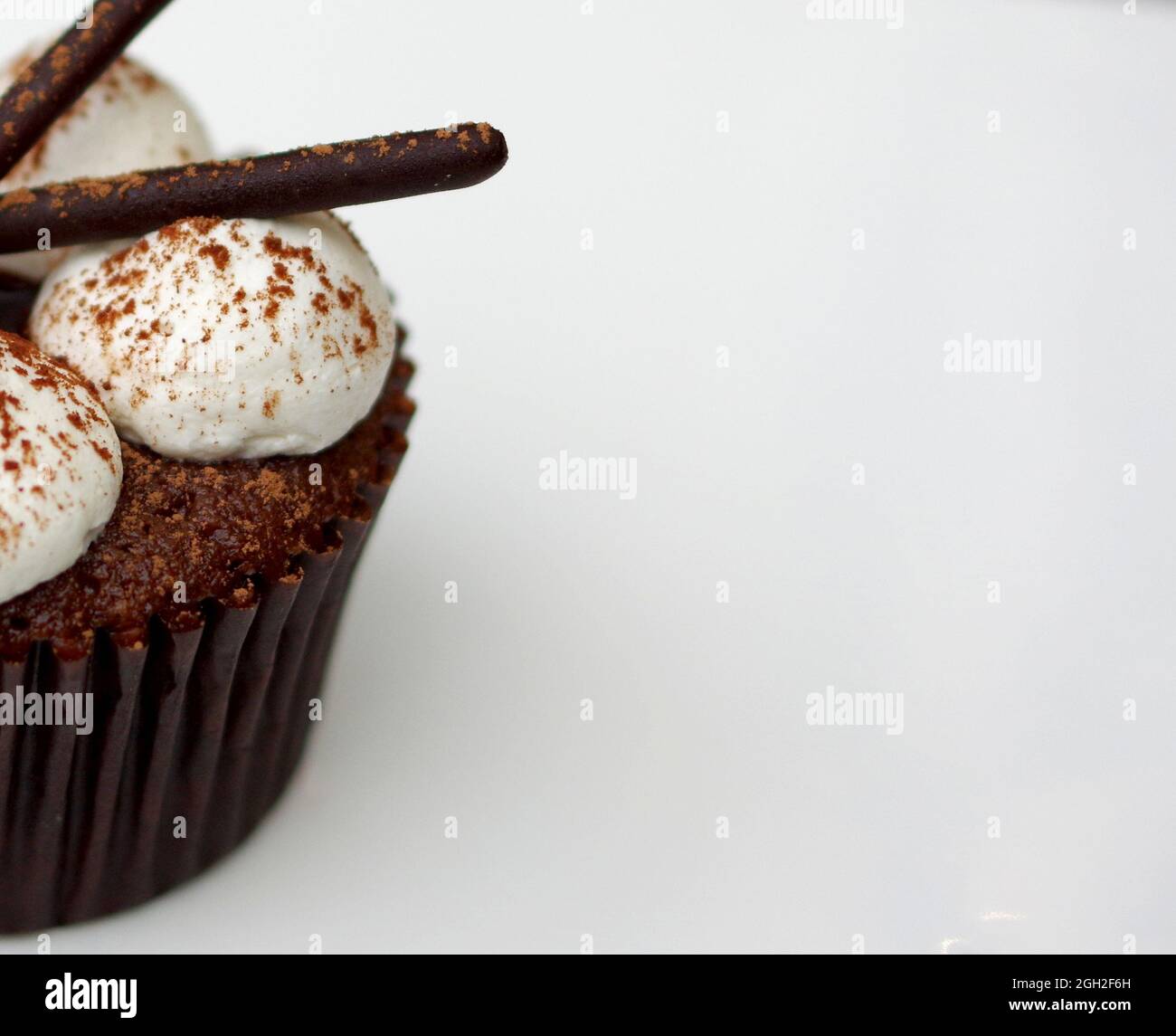 Chocolate cupcake with cocoa powder on cream topping and pocky biscuit ...
