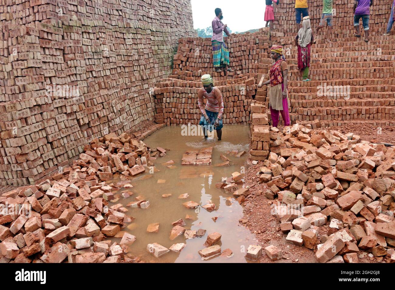 Workers hold bricks on their heads after taking them out of the ovens ...