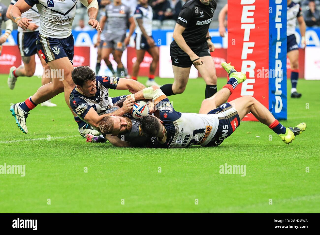 Sam Tomkins (29) of Catalans Dragons is held up by Lewis Dodd (21) and ...