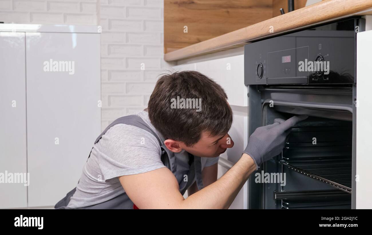 Worker turns levers checking broken oven in spacious kitchen Stock ...