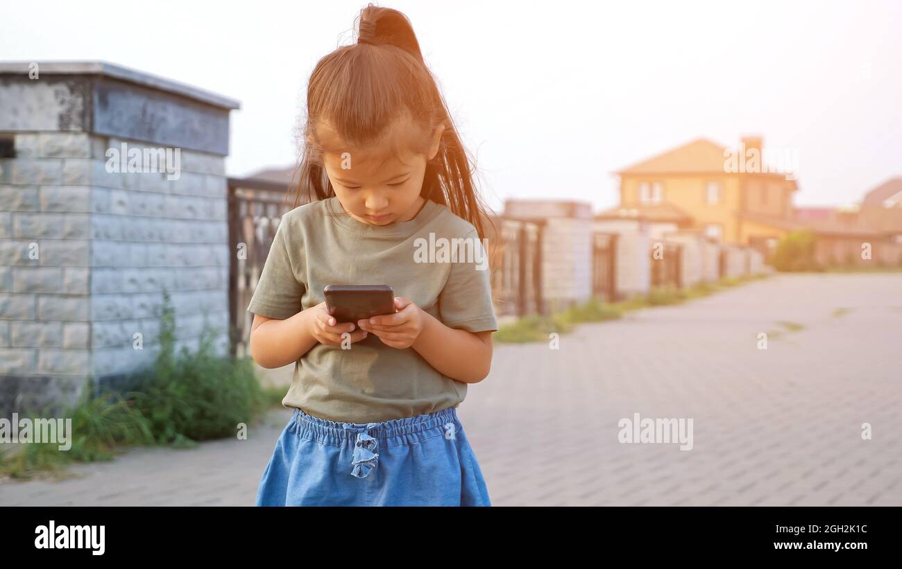 Concentrated Asian girl texts message on phone on waterfront Stock ...