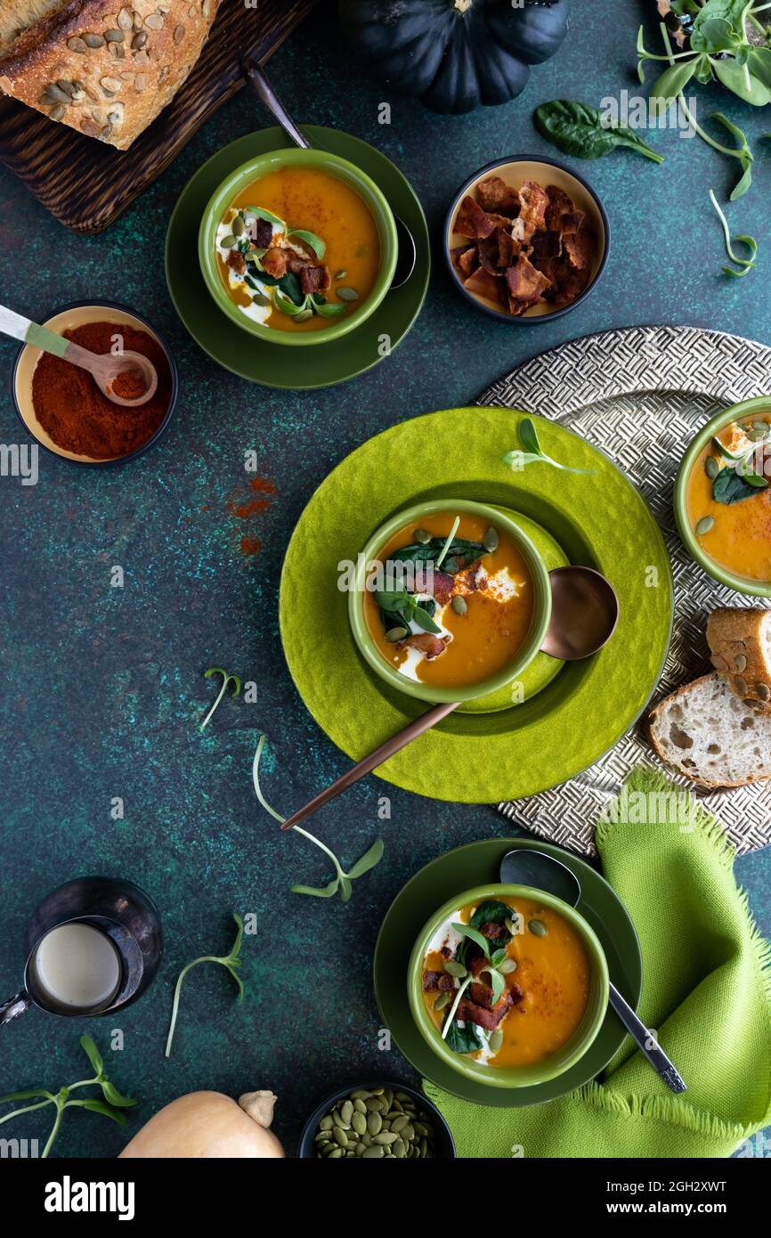 Top down vertical view of bowls of butternut squash soup surrounded by ...