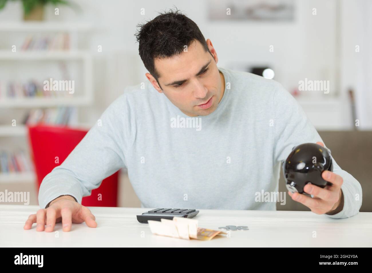Young man worried piggy bank hi-res stock photography and images - Alamy