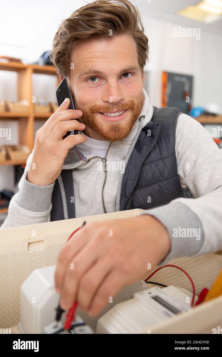 electrician using a multimeter and talking on smartphone Stock Photo ...