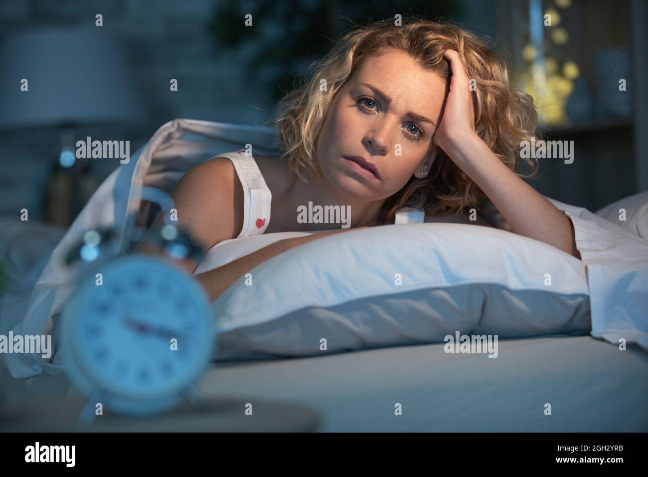 woman in her bed looks on clock Stock Photo - Alamy
