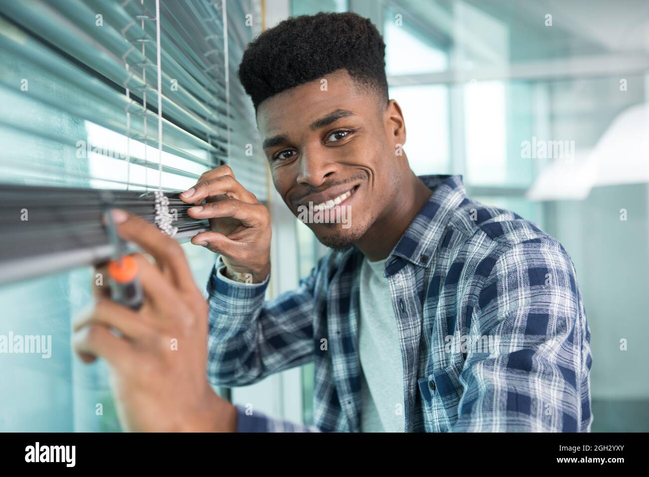 man repairing window blind with a screwdriver Stock Photo - Alamy
