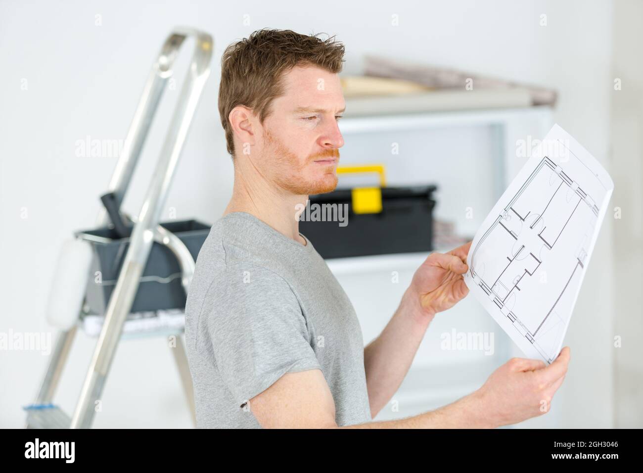 handsome man with drawings on ladder in the white interior Stock Photo ...