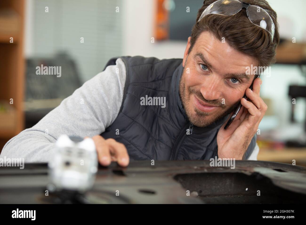 man talking on smartphone while working on vehicle bodywork Stock Photo ...