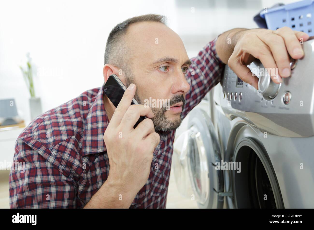 mature man getting advice on how to use washing machine Stock Photo - Alamy