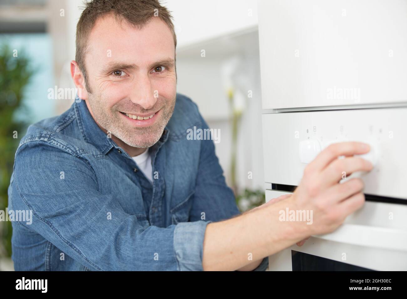 happy man using an oven in the kitchen Stock Photo - Alamy