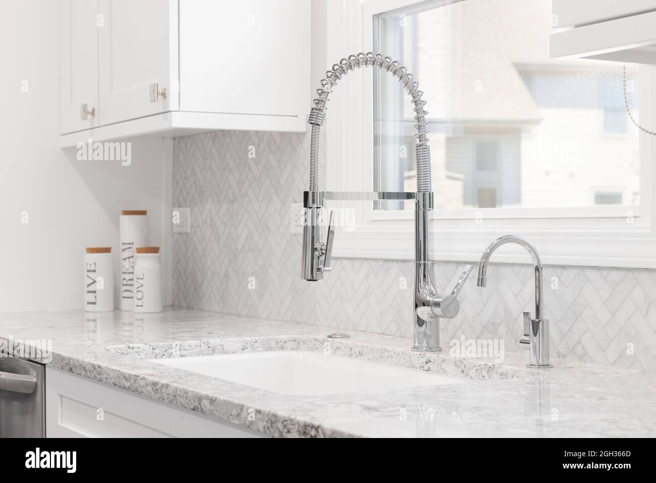 A kitchen sink detail shot in a renovated kitchen with white cabinets ...