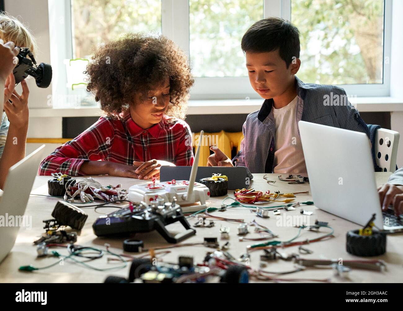 Asian school kid boy helping African girl using tablet programming ...