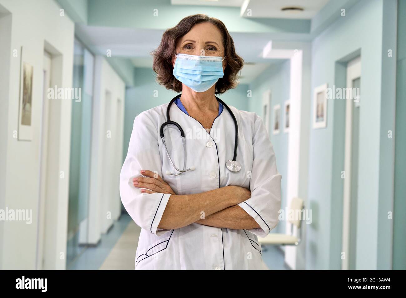 Old female doctor wearing face mask and medical coat standing in ...