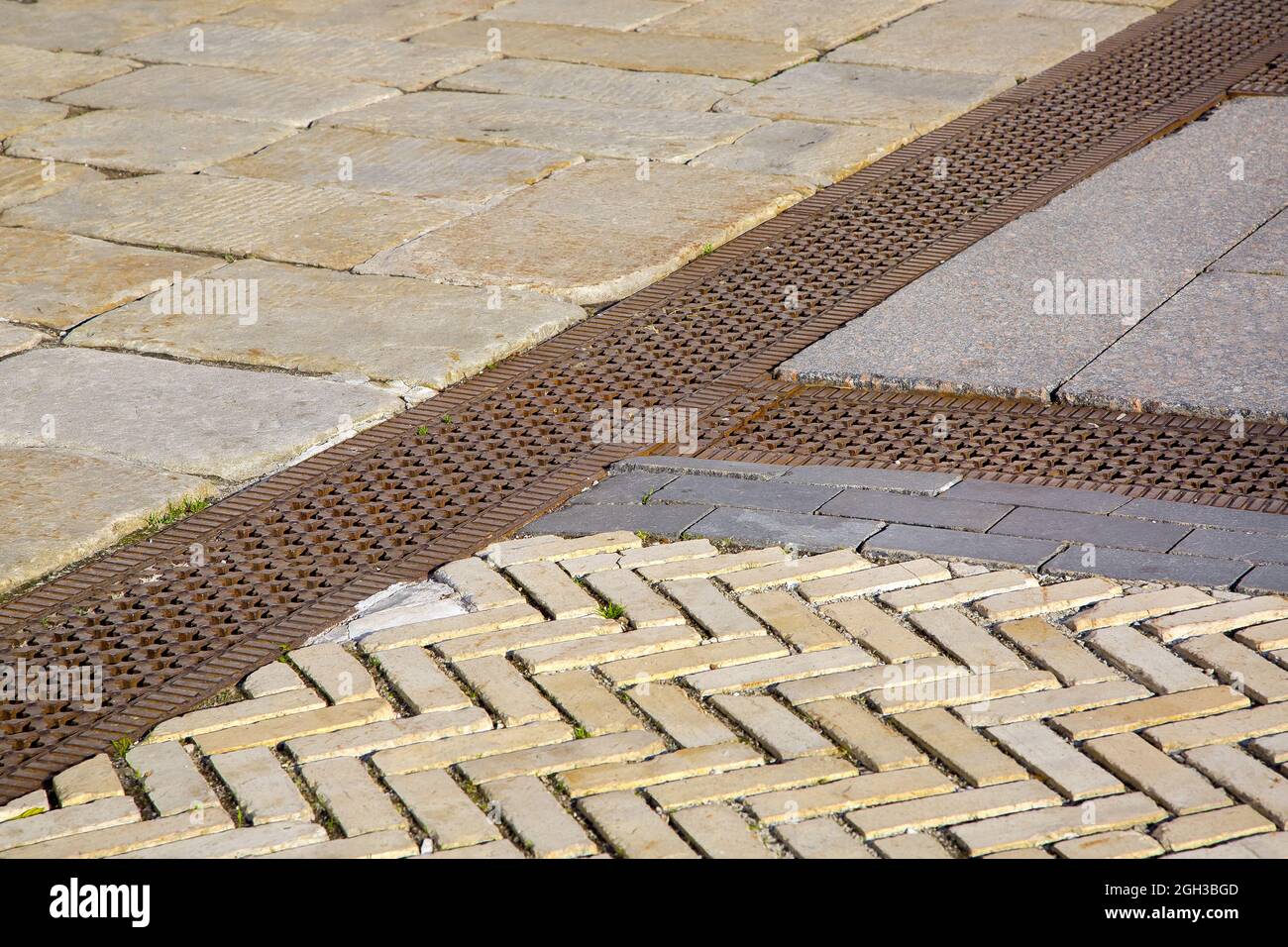 a drainage ditch covered with an iron patterned lattice on a sidewalk ...