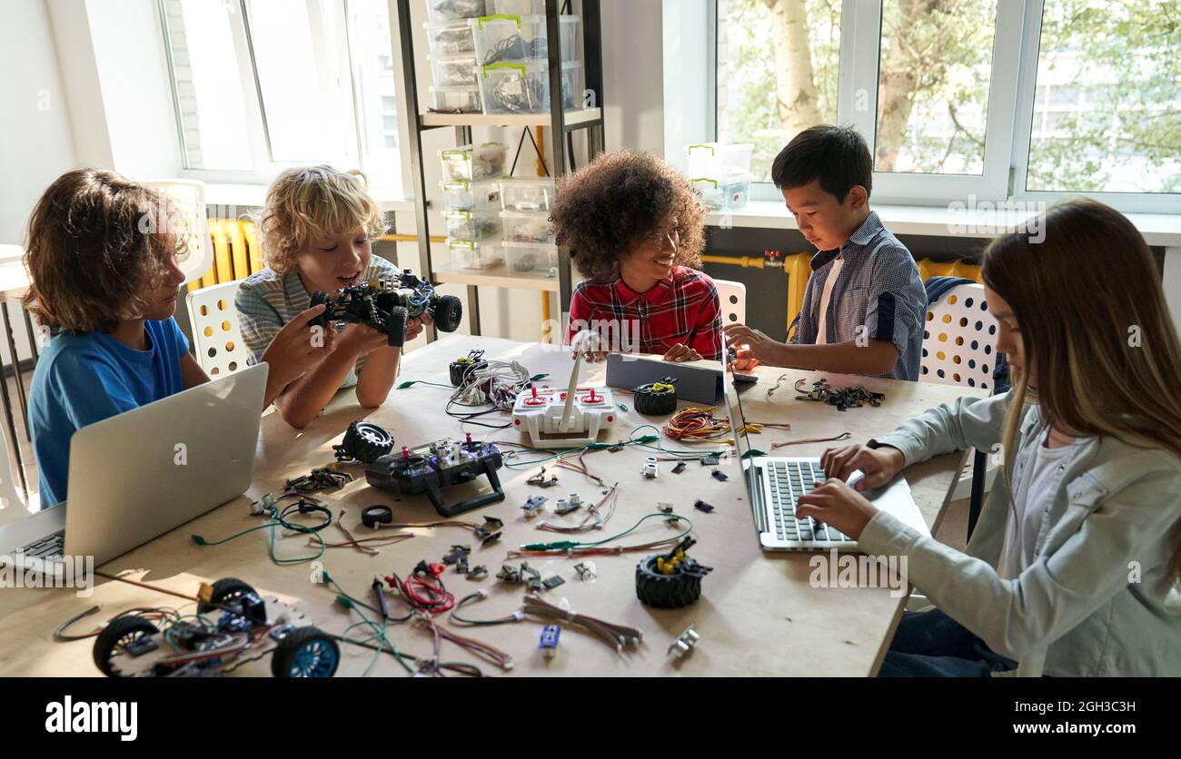 Diverse school children students group building robotic cars using ...
