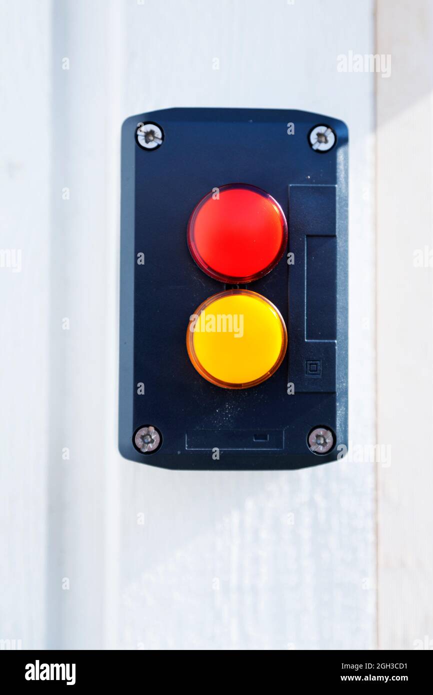 a red and yellow button mounted on the wall Stock Photo - Alamy