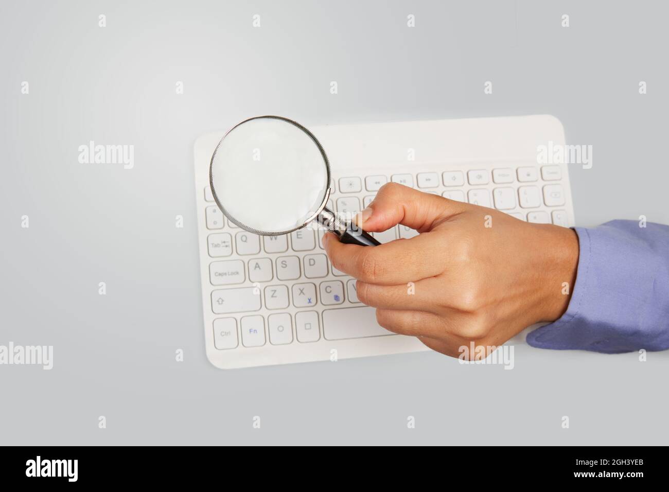 Holding a magnifying glass on a keyboard. Business and cyber security ...