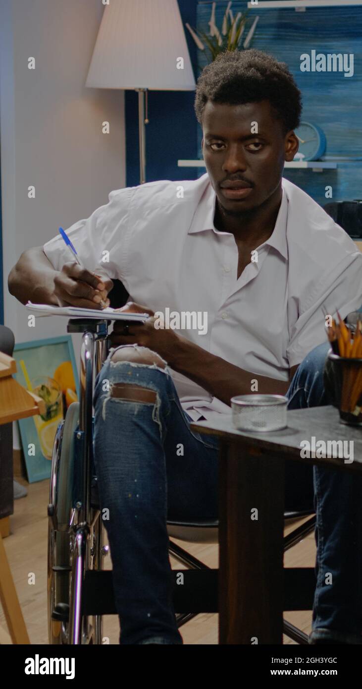 Black disabled artist working on modern drawing at studio sitting in ...