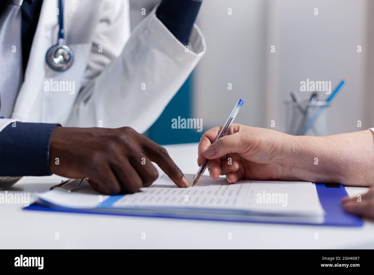 Close up of hands on desk at healthcare clinic. Caucasian patient ...