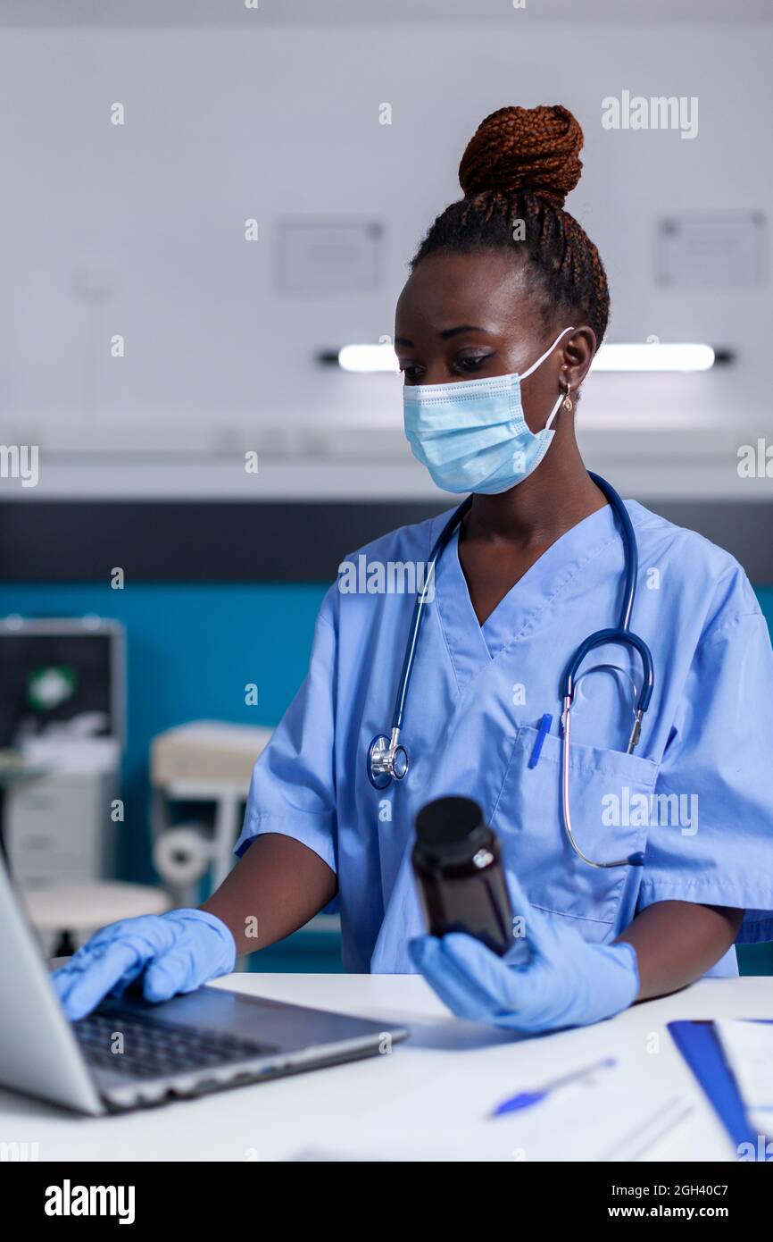 Portrait of african american nurse typing on laptop keyboard while ...