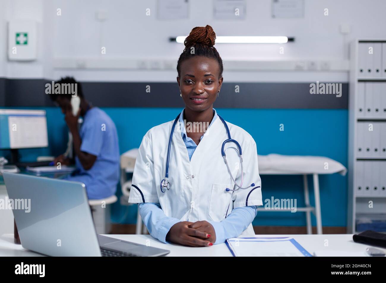 Portrait of african ethnicity doctor looking at camera while sitting at ...