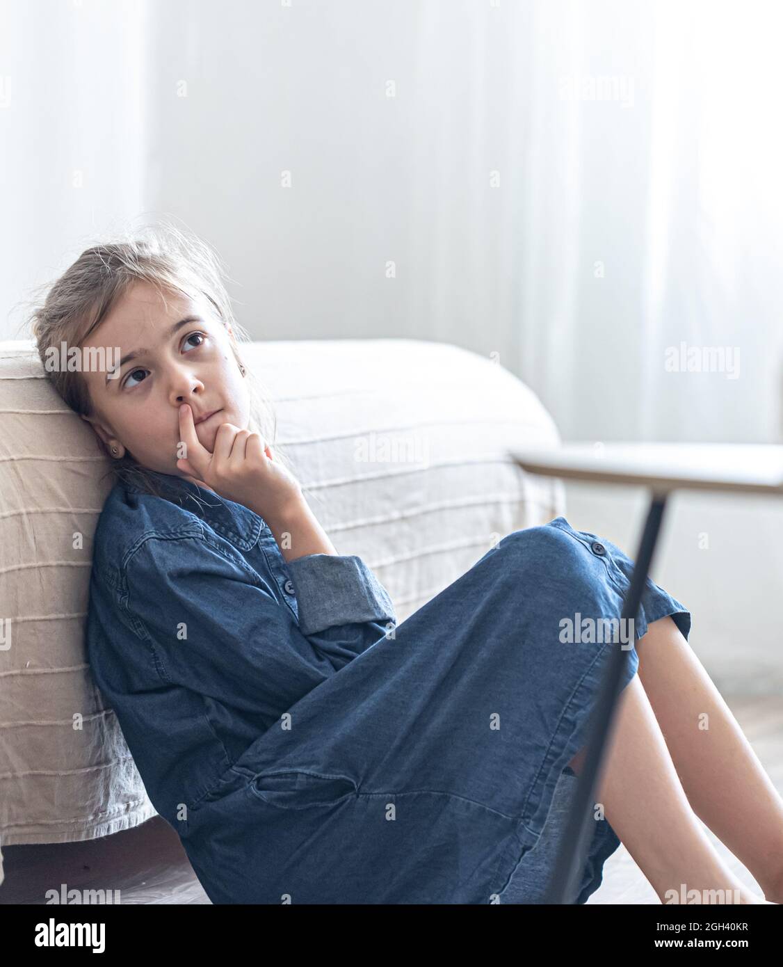A tired little girl is sitting in a room on the floor Stock Photo - Alamy