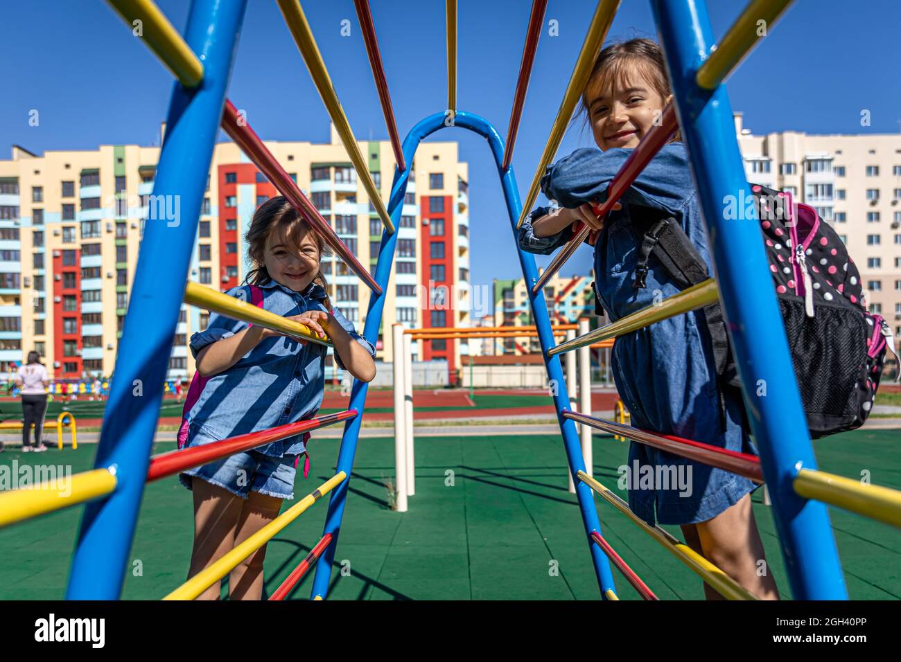 Two little girls, elementary school students, play on the playground ...