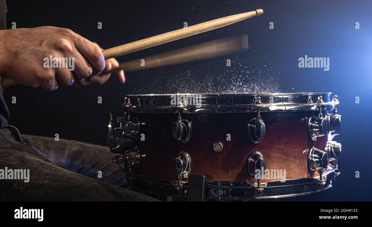 Drummer using drum sticks hitting snare drum with splashing water on ...