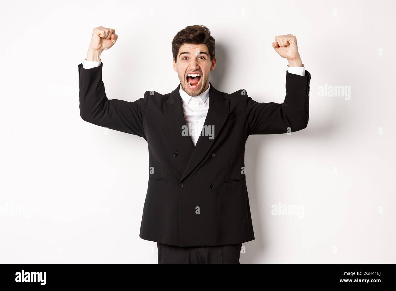 Successful handsome businessman triumphing, raising hands up and ...