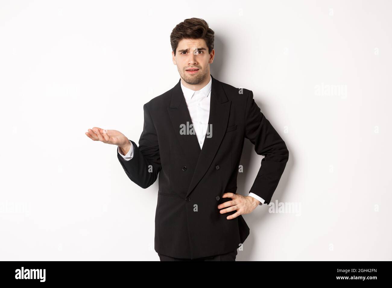 Image of confused handsome man in formal suit, raising hand and ...