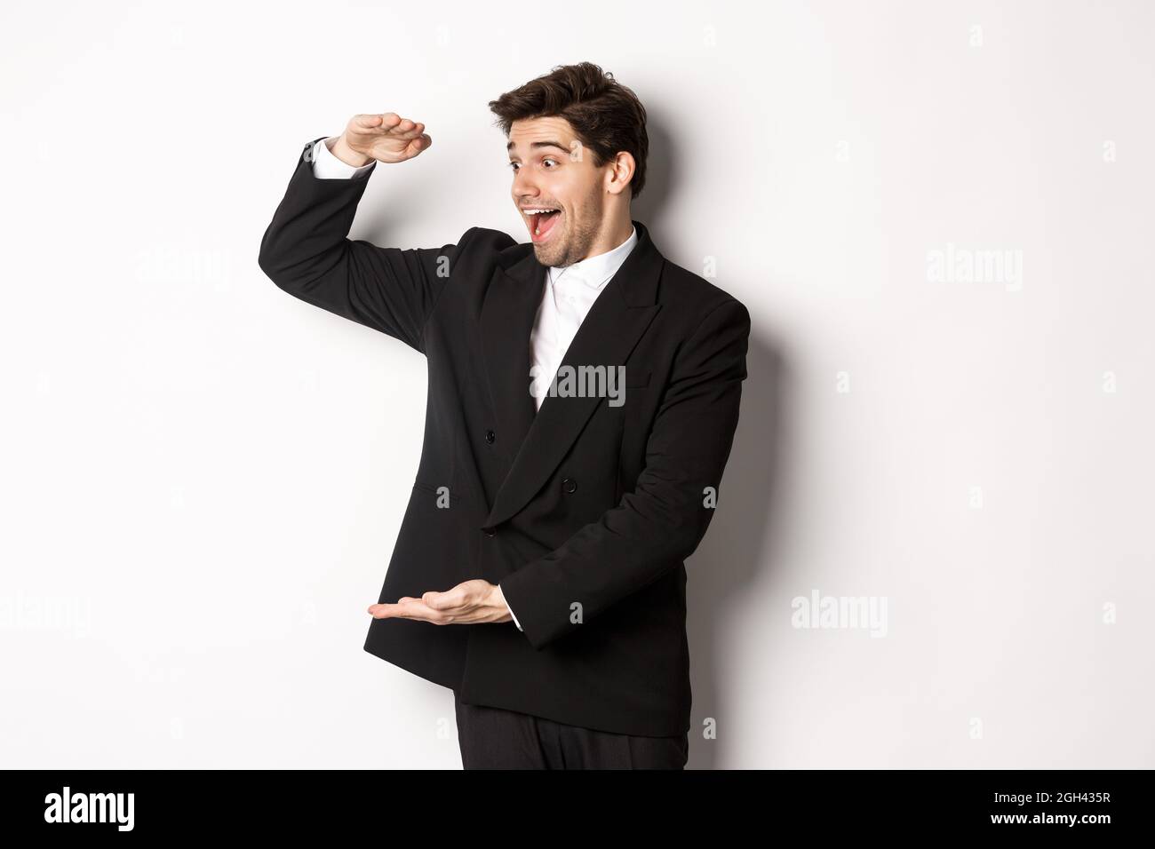 Portrait of excited handsome man in suit, shaping big object on copy ...