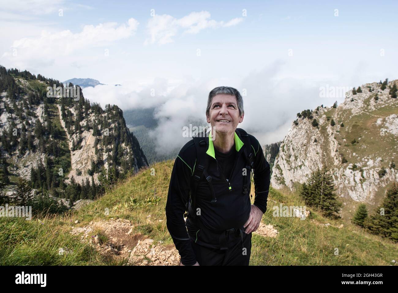 A man on a mountain hiking trail climbs over rocks Stock Photo - Alamy