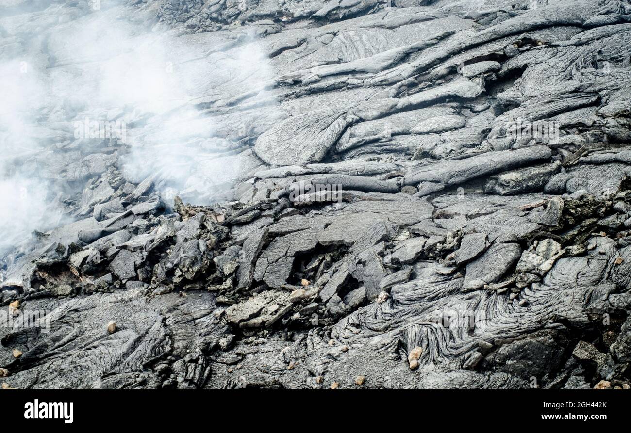 A high angle shot of a landscape with rough volcanic ash and smoke ...
